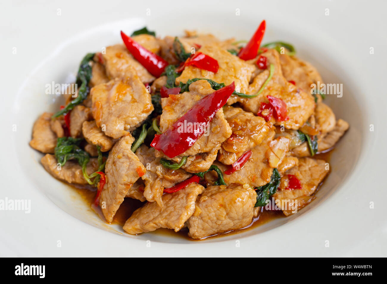 Stir-fried hot and spicy pork with holy basil on white background Stock ...