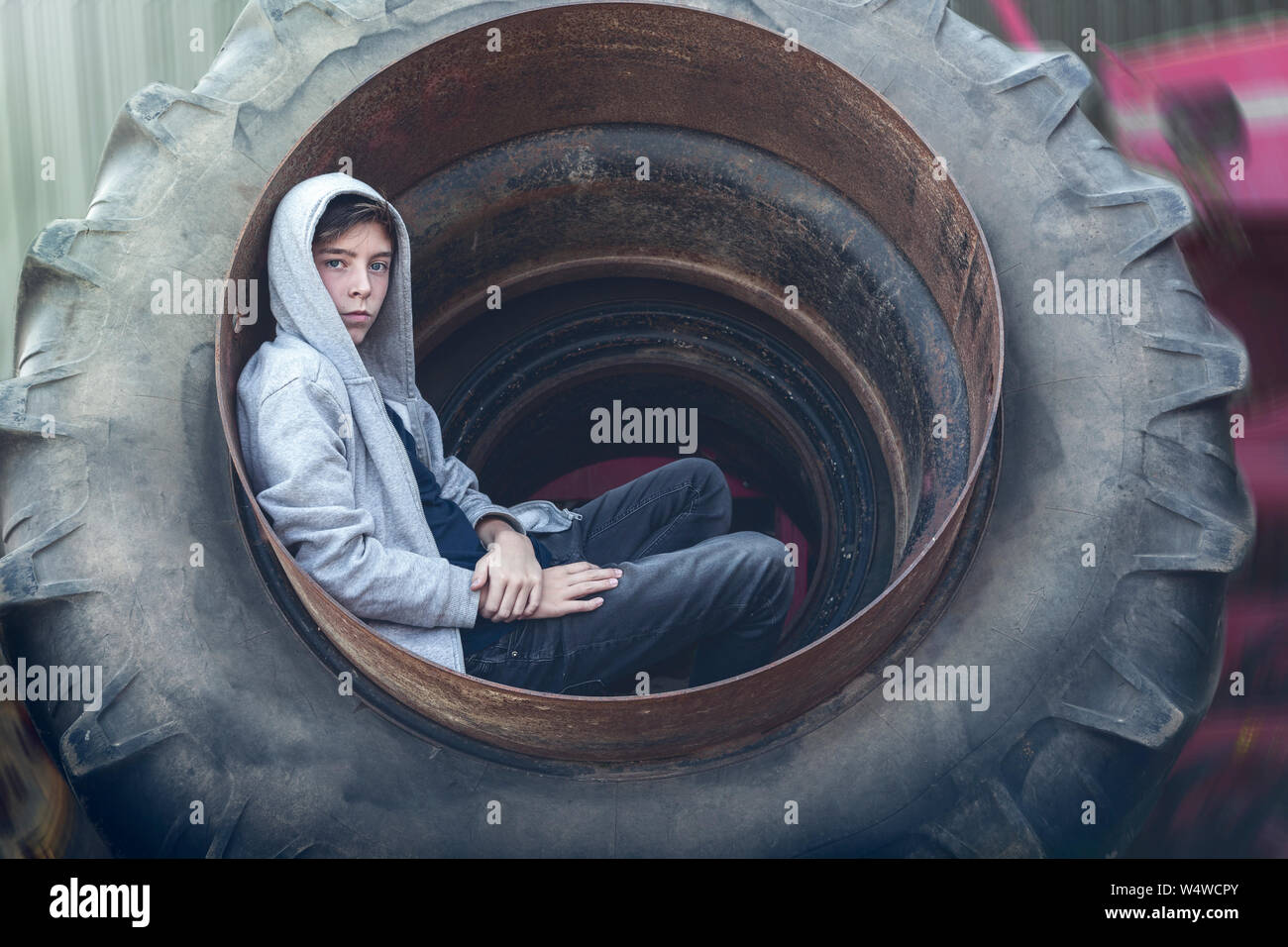 portrait of a young man sitting in a huge wheel of a tractor Stock ...