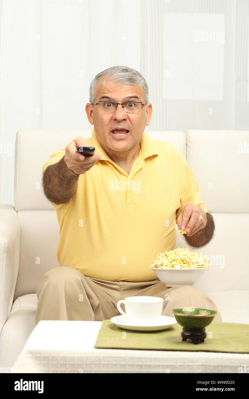 Old man sitting on a couch and watching television Stock Photo - Alamy