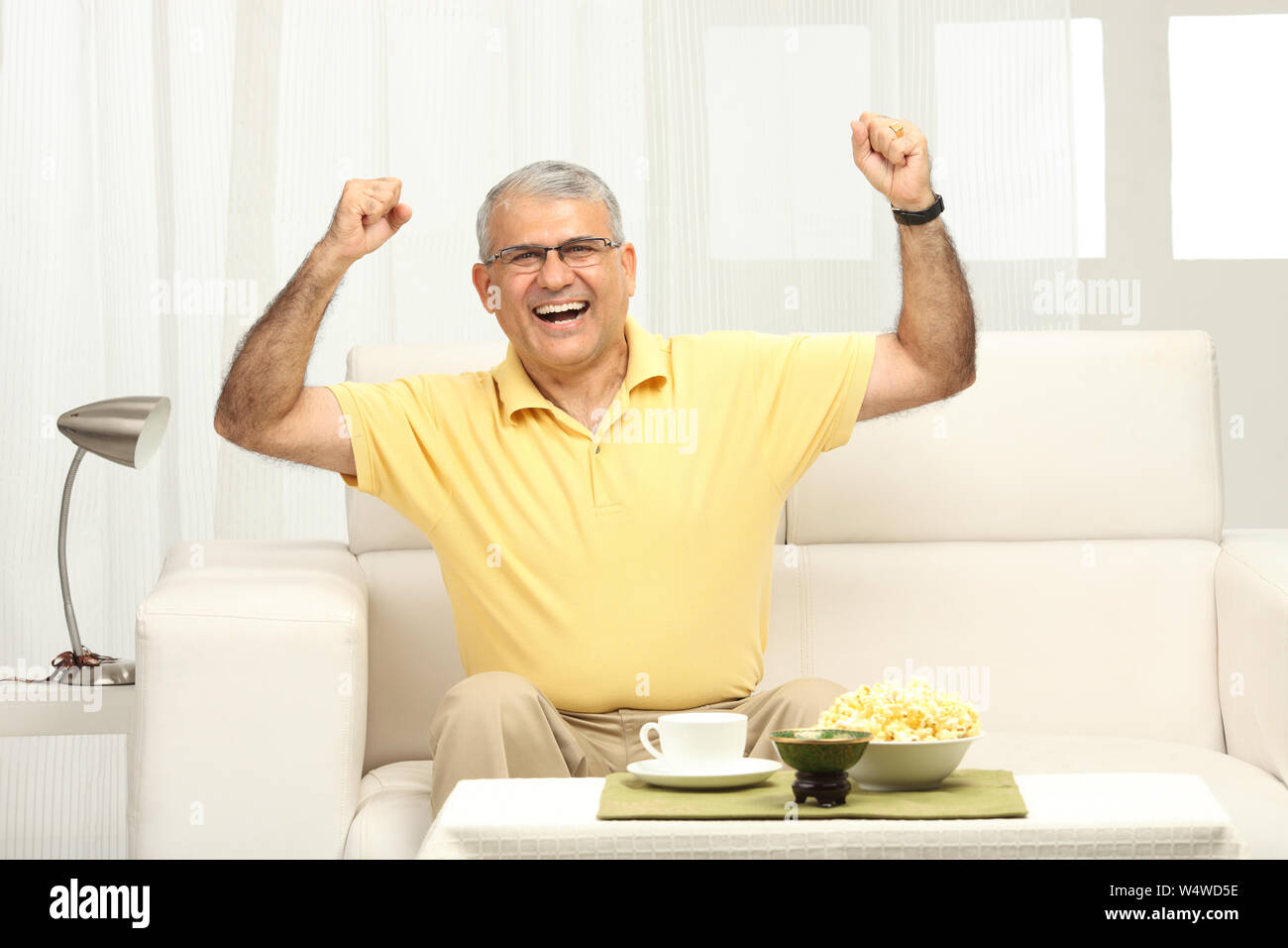 Man sitting on a couch and smiling his arms raised Stock Photo - Alamy
