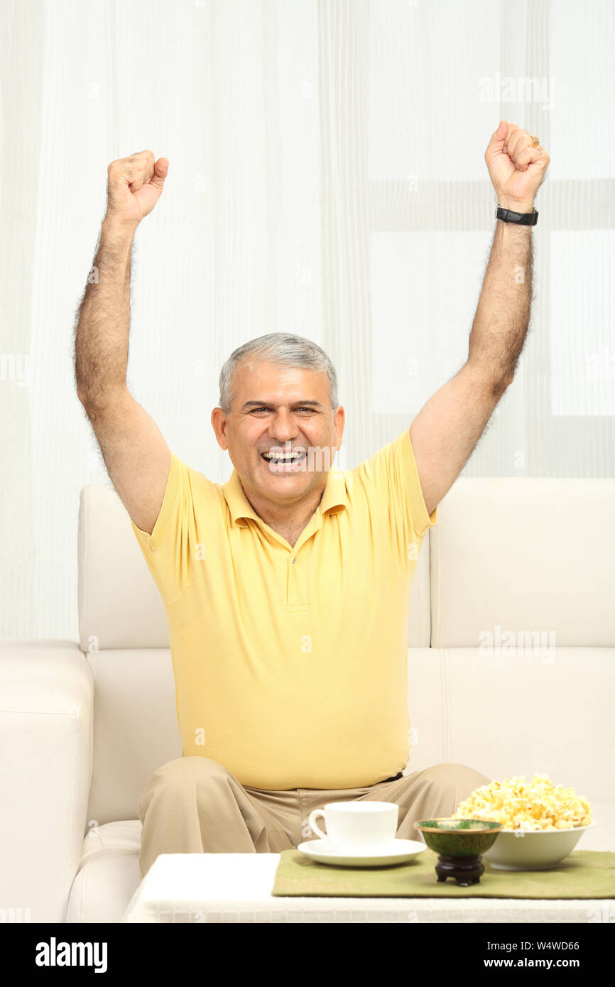 Old man watching television and cheering Stock Photo - Alamy