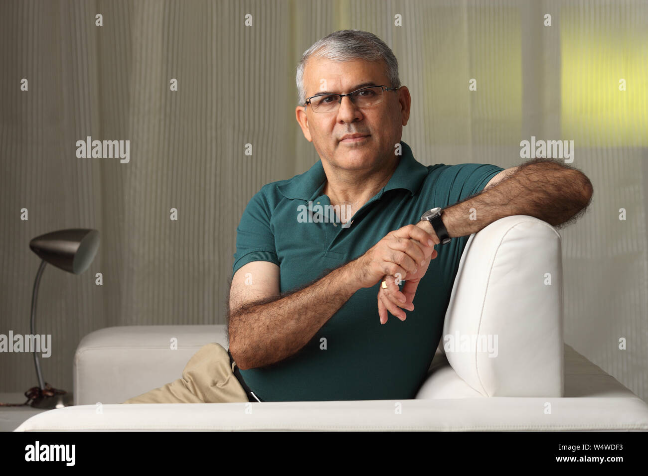 Man sitting on a couch at home Stock Photo - Alamy