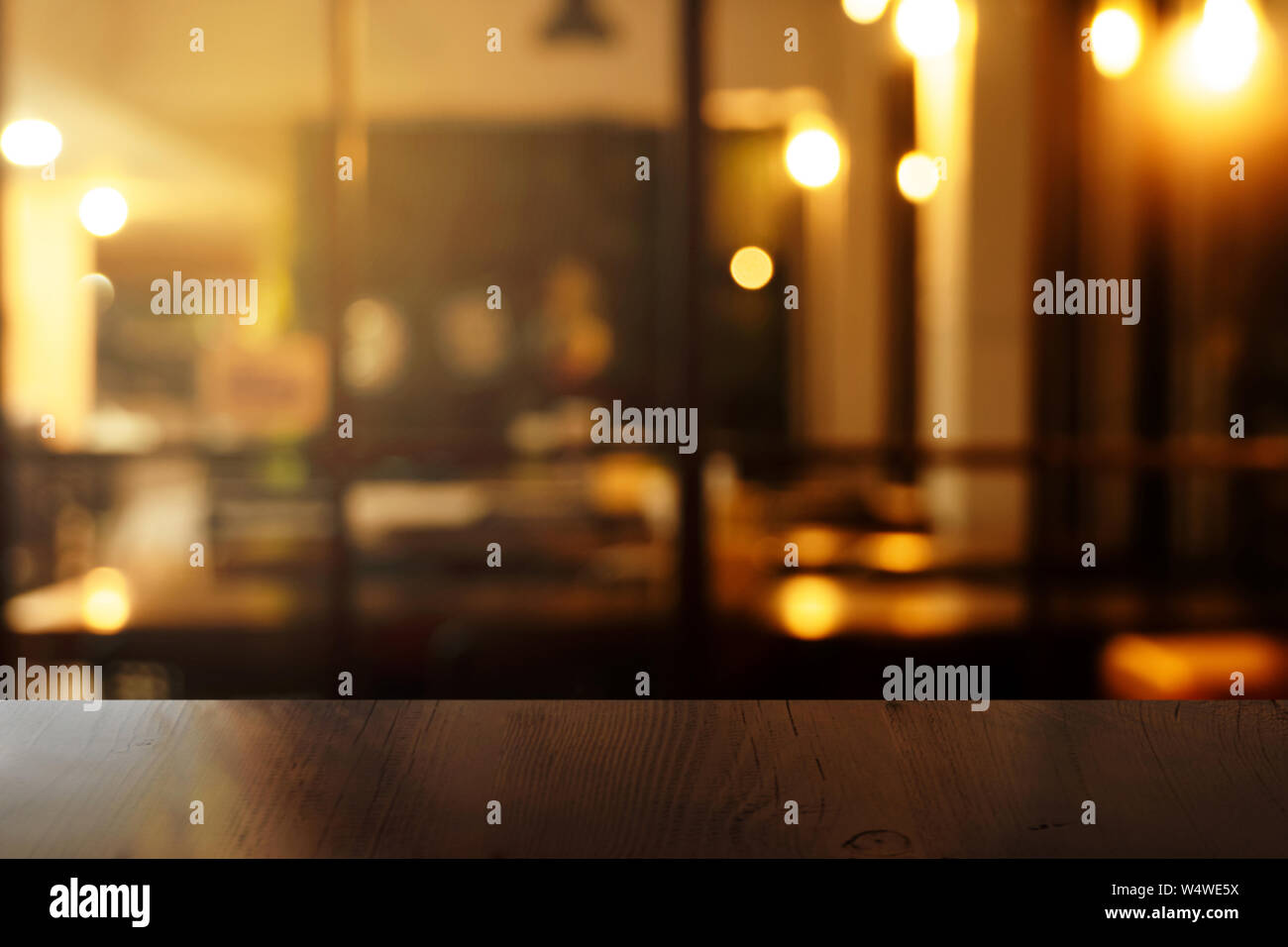 top of brown wood table with blur orange light at bar or pub in the ...