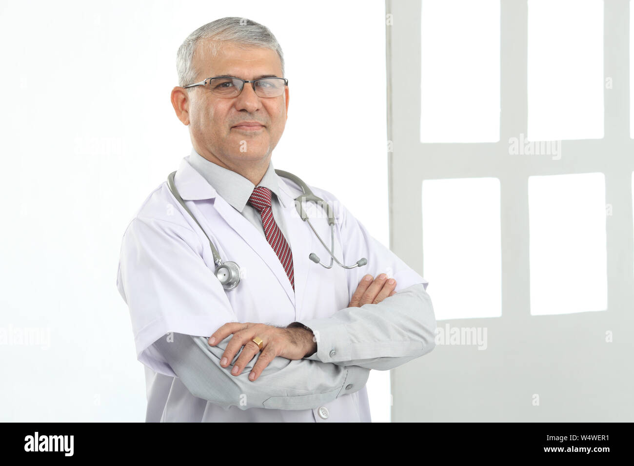 Male doctor standing with his arms crossed Stock Photo - Alamy