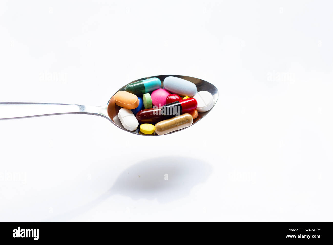 Various types of tablets, capsules and pills on spoon with white ...