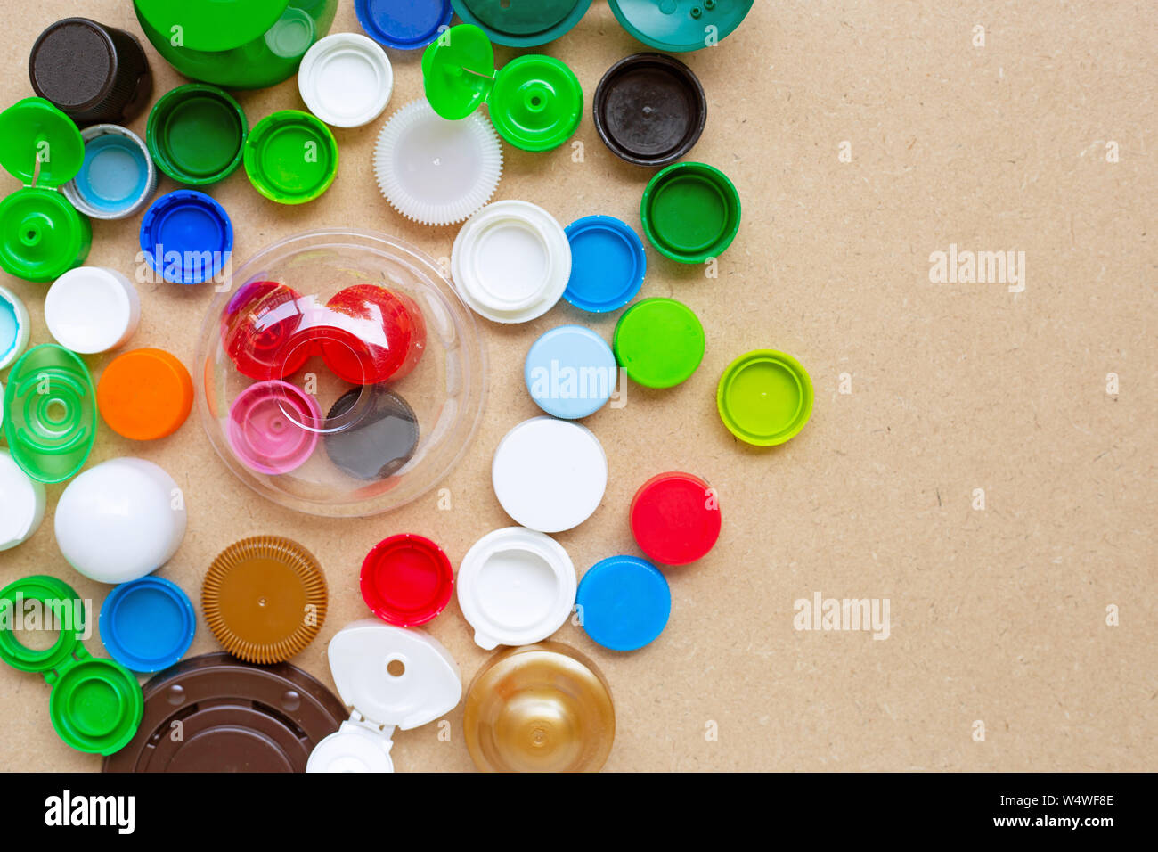 Colorful plastic bottle caps and plastic glass lid on plywood ...
