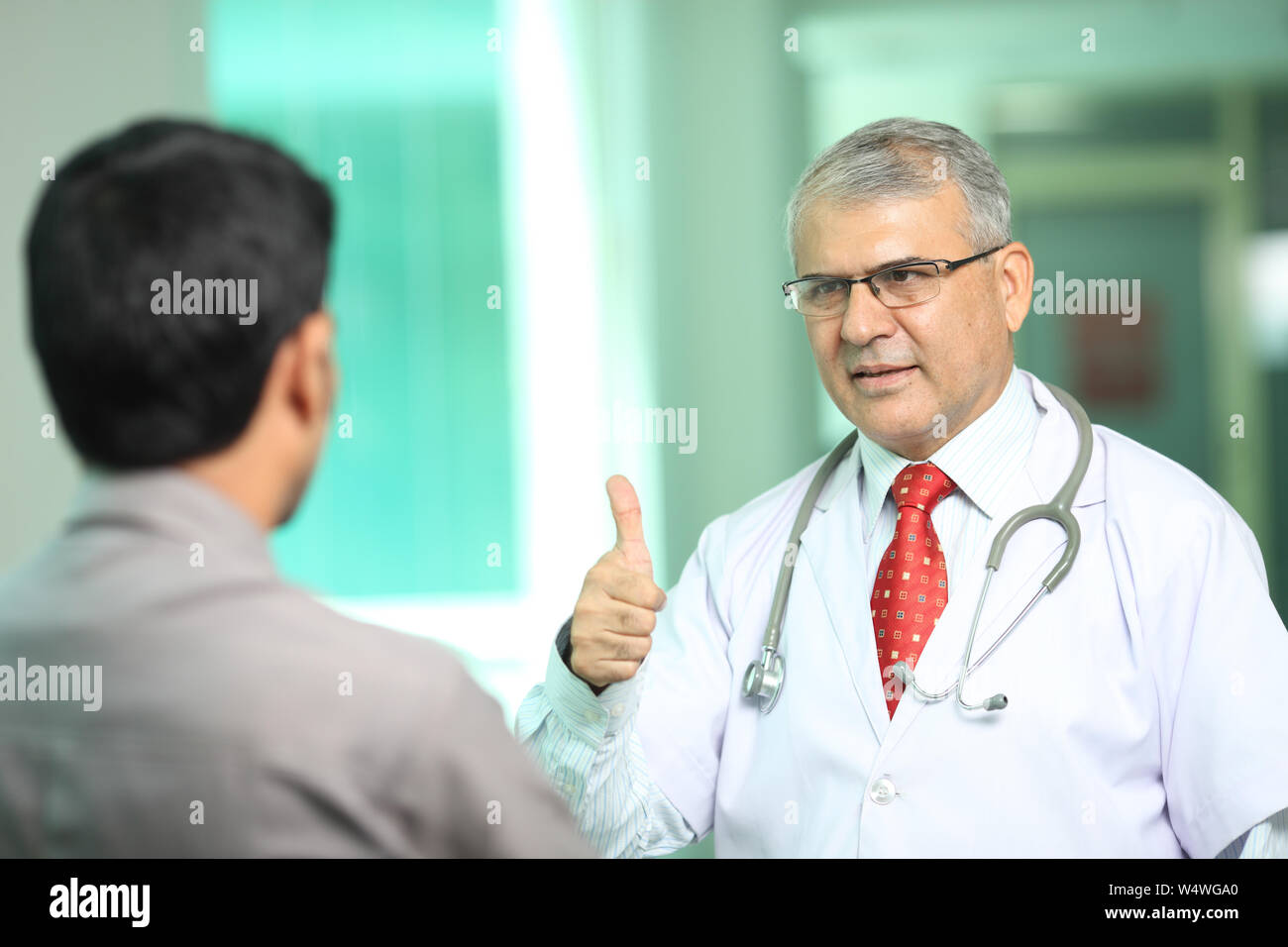 Male doctor showing thumbs up sign to patient Stock Photo - Alamy