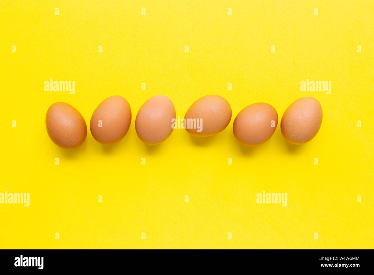 Eggs on yellow background. Top view Stock Photo - Alamy