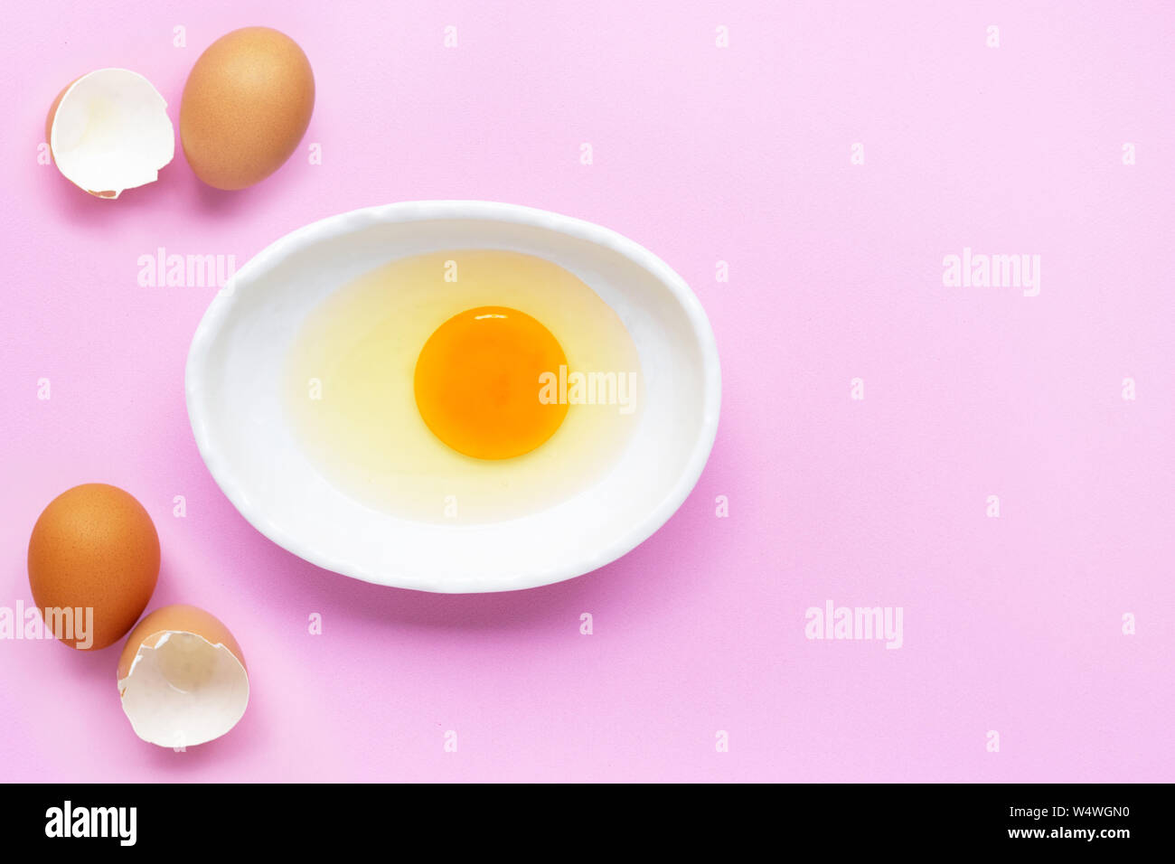 Egg yolk and white in a bowl on pink background. Top view Stock Photo ...
