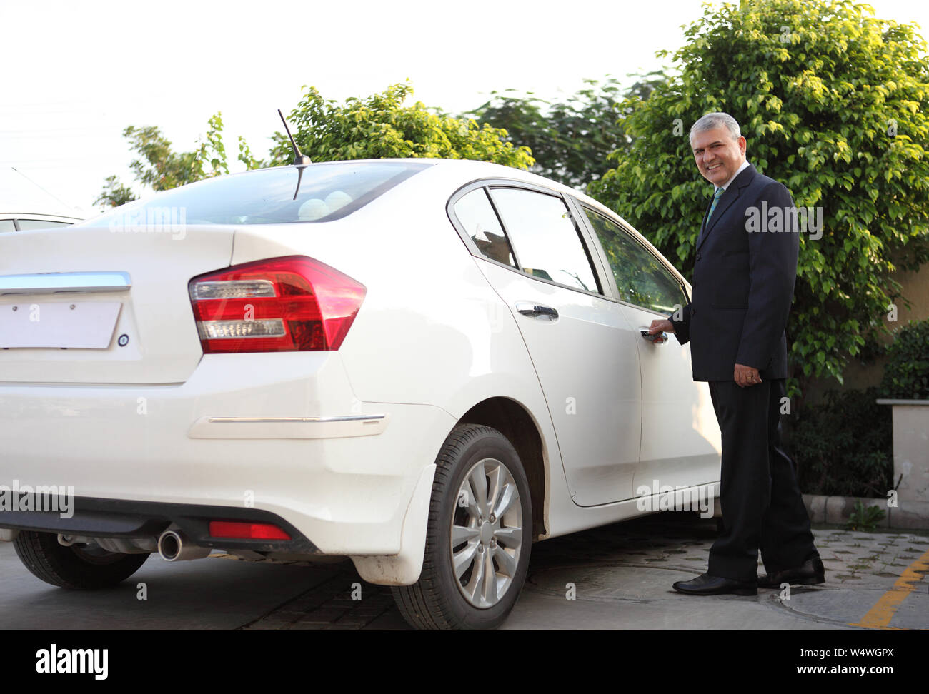 Businessman opening car door and smiling Stock Photo - Alamy