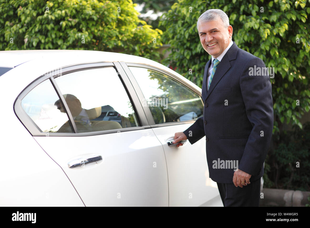 Businessman opening car door and smiling Stock Photo - Alamy