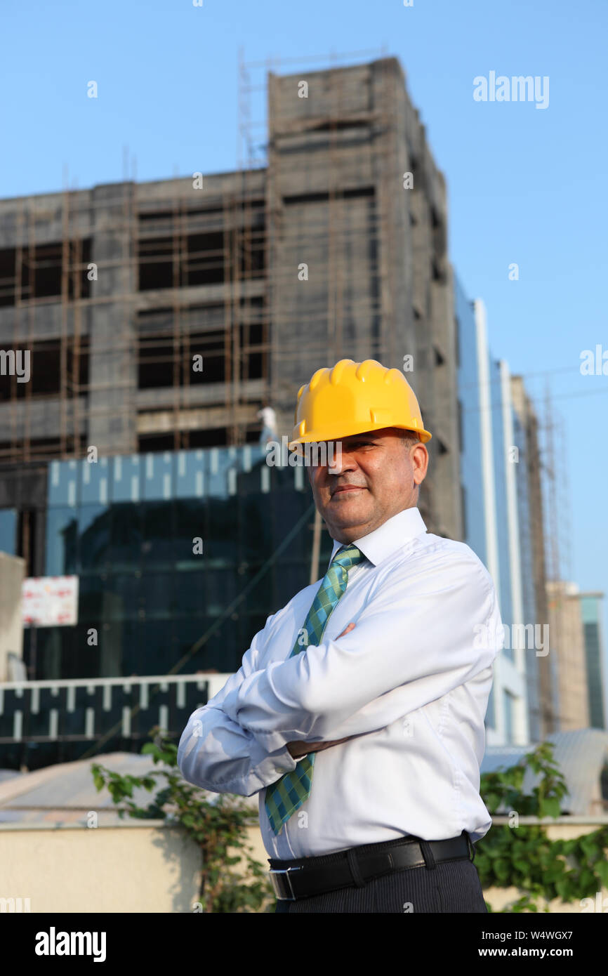 Architect standing with arms crossed at construction site Stock Photo ...