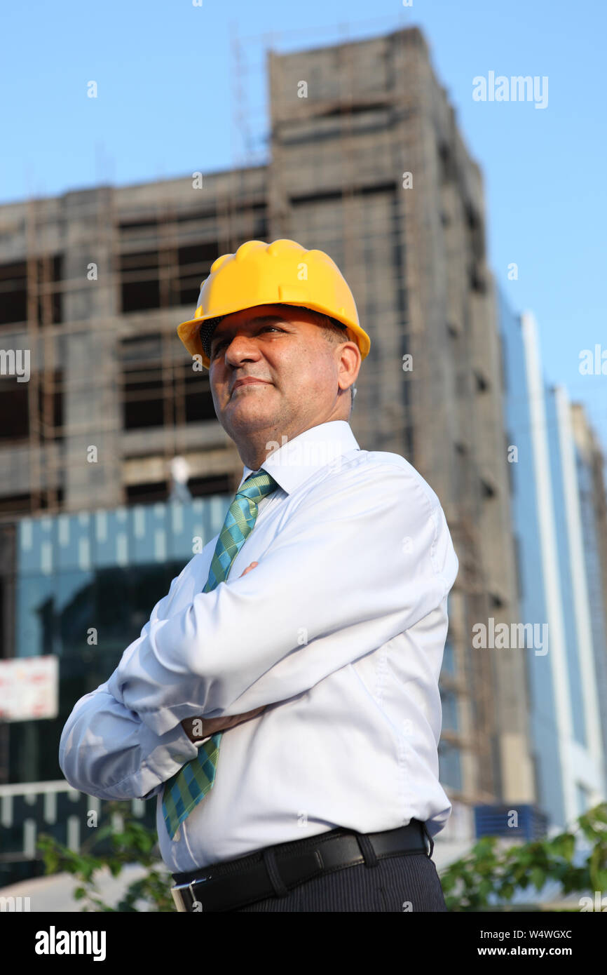 Indian architect standing with arms crossed at construction site Stock ...