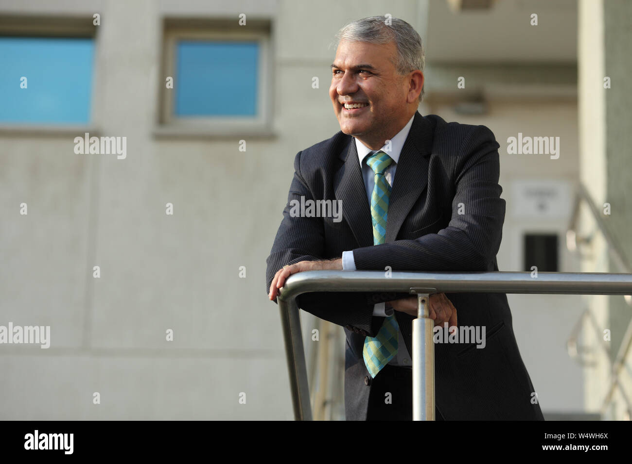 Indian businessman leaning against railing Stock Photo - Alamy
