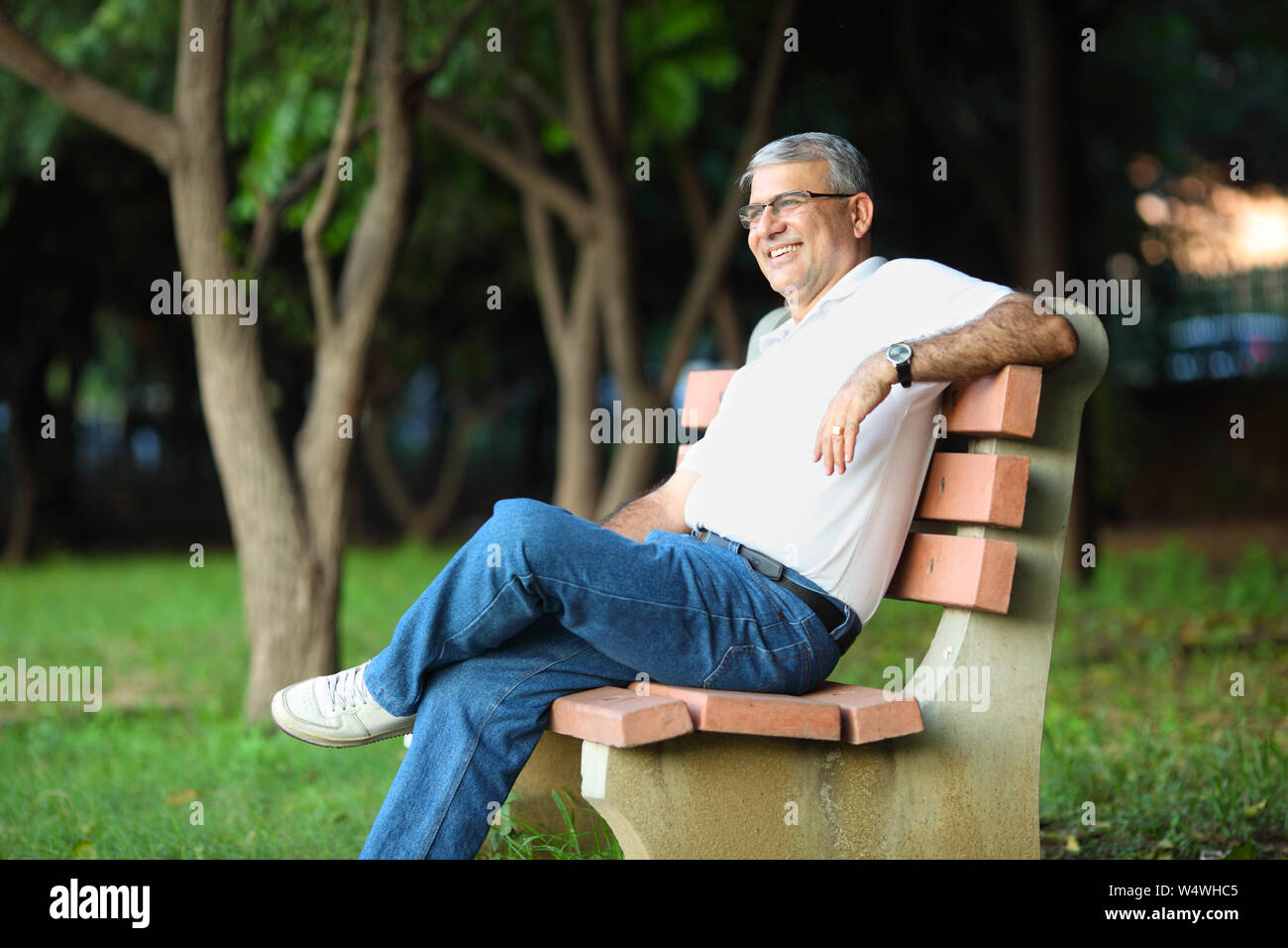 Man sitting on a park bench and smiling Stock Photo - Alamy