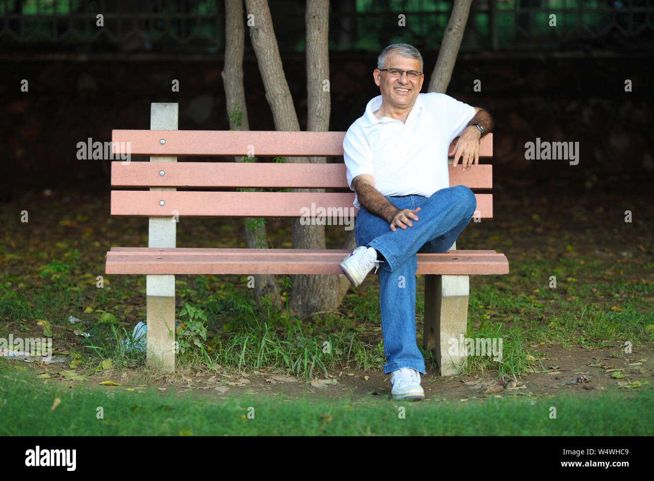 Man sitting on a park bench and smiling Stock Photo - Alamy