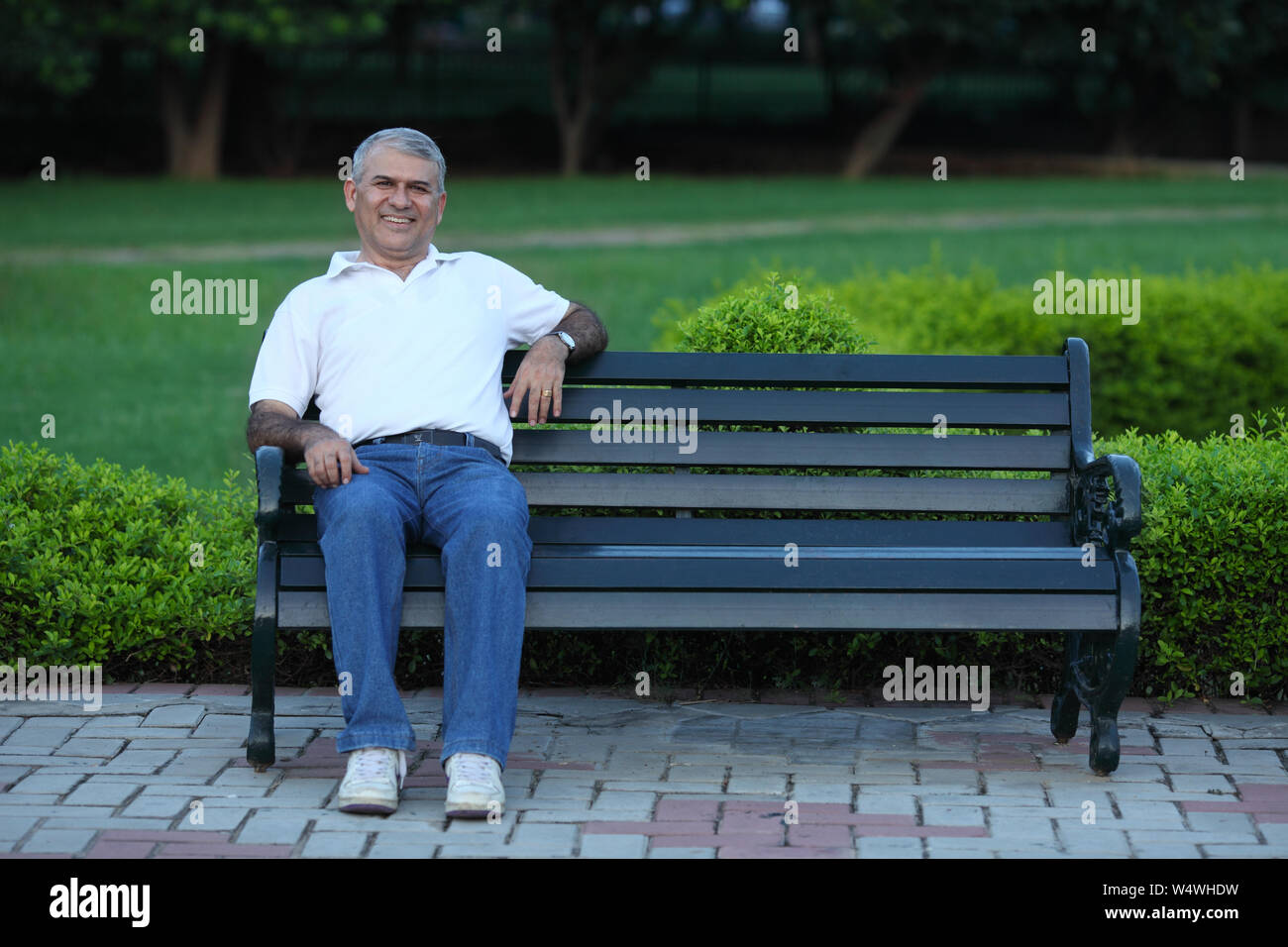 Man sitting on a park bench and smiling Stock Photo - Alamy
