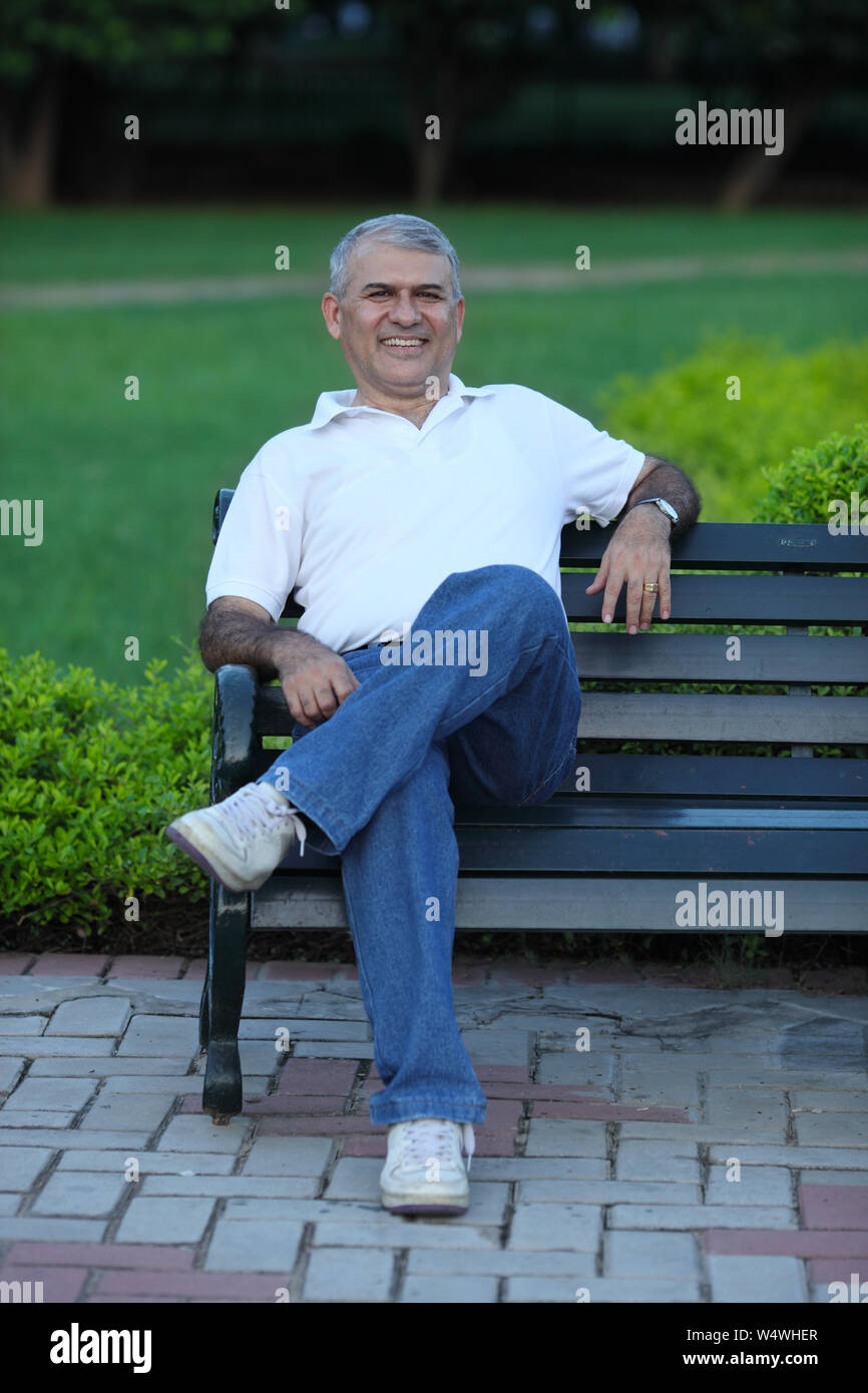 Man sitting on a park bench and smiling Stock Photo - Alamy
