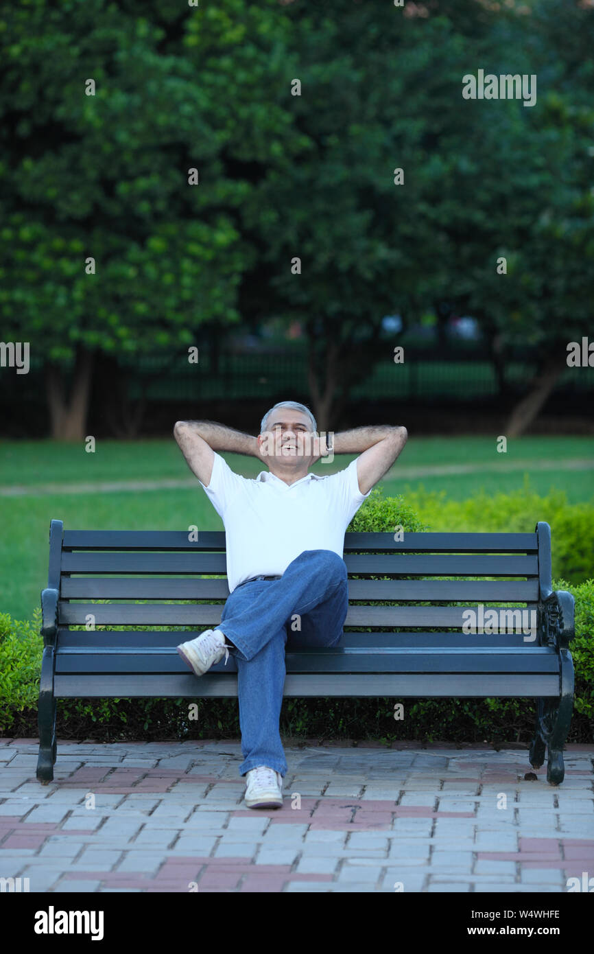 Man sitting on a park bench and smiling Stock Photo - Alamy
