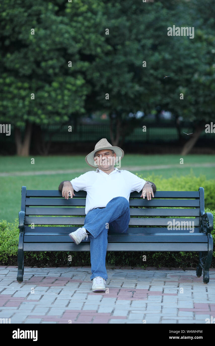 Man sitting on a park bench and smiling Stock Photo - Alamy