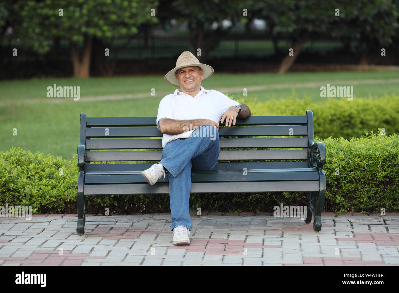 Man sitting on a park bench and smiling Stock Photo - Alamy