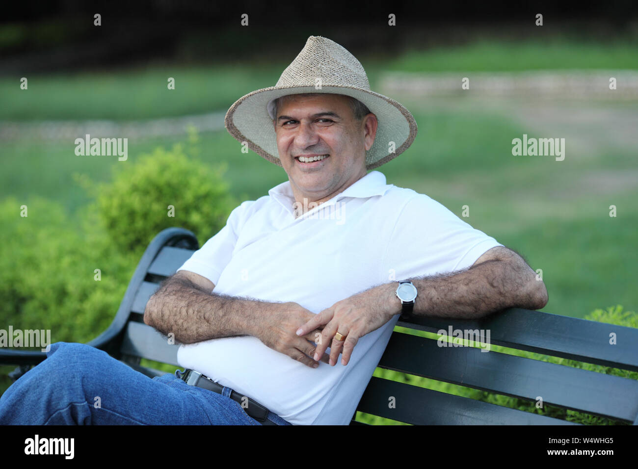 Man sitting on a park bench and smiling Stock Photo - Alamy