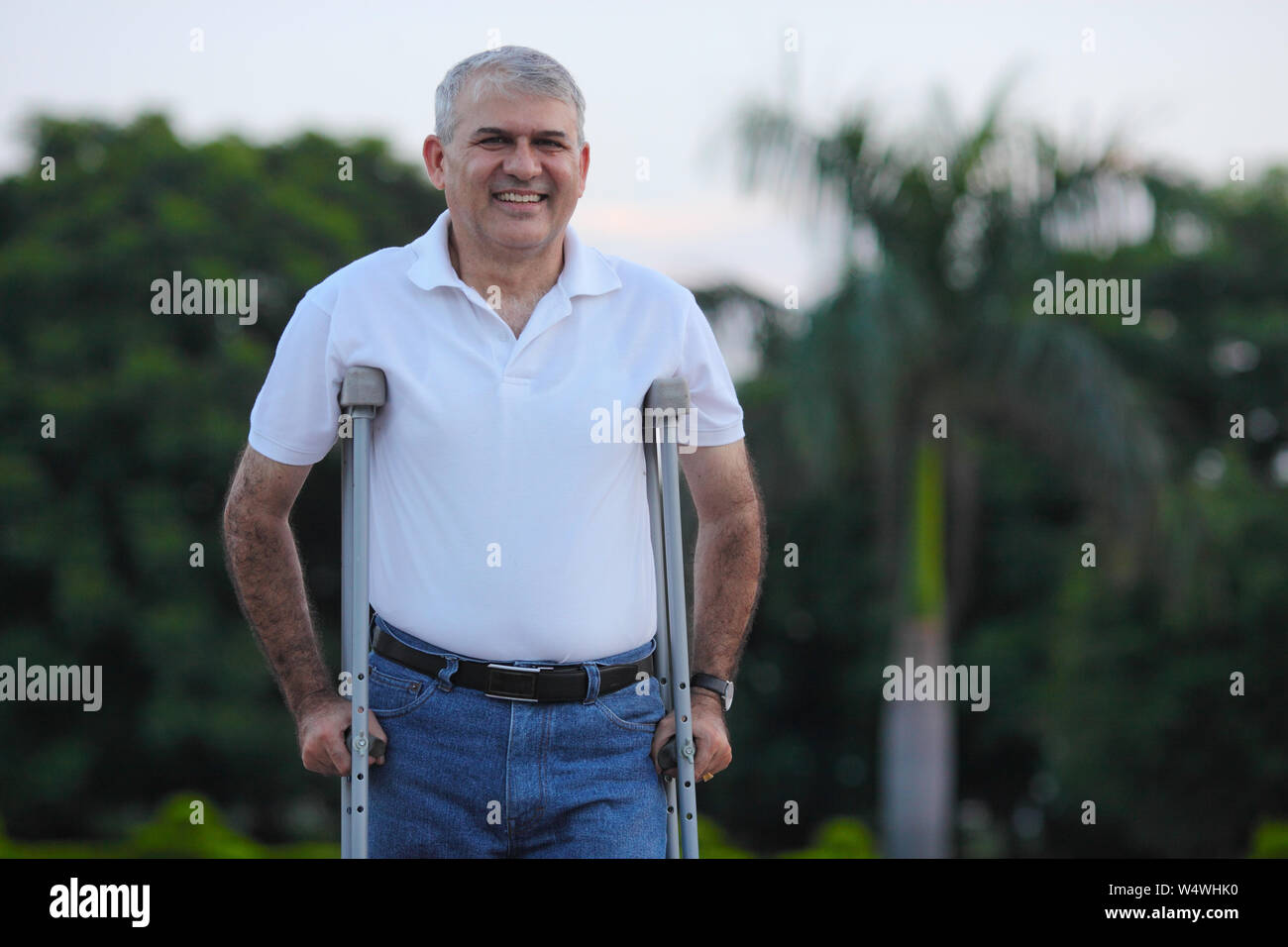 Old man standing with the help of crutches Stock Photo - Alamy