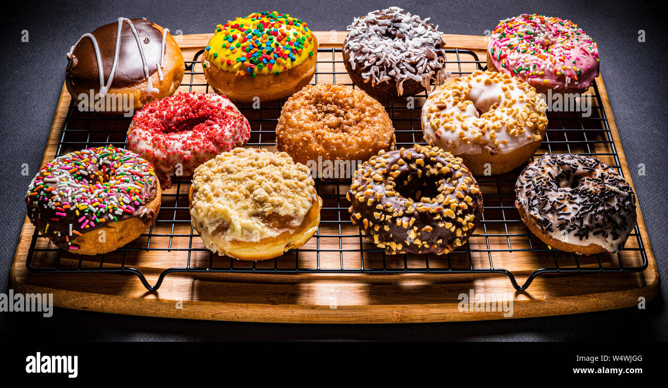 assorted donuts on wire rack on wooden cutting board Stock Photo - Alamy