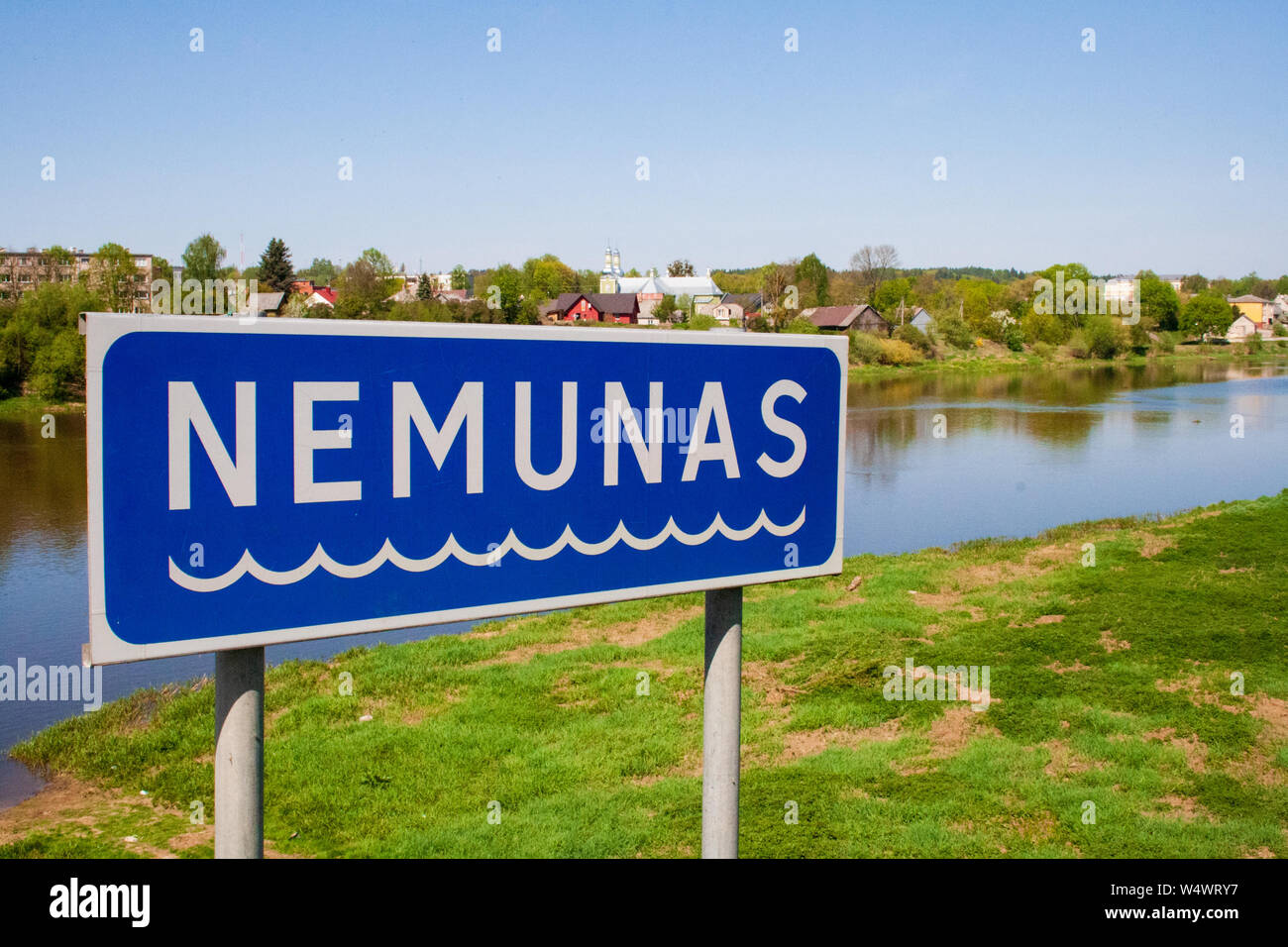 Road sign and panorama of Nemunas river with church, wooden houses and ...