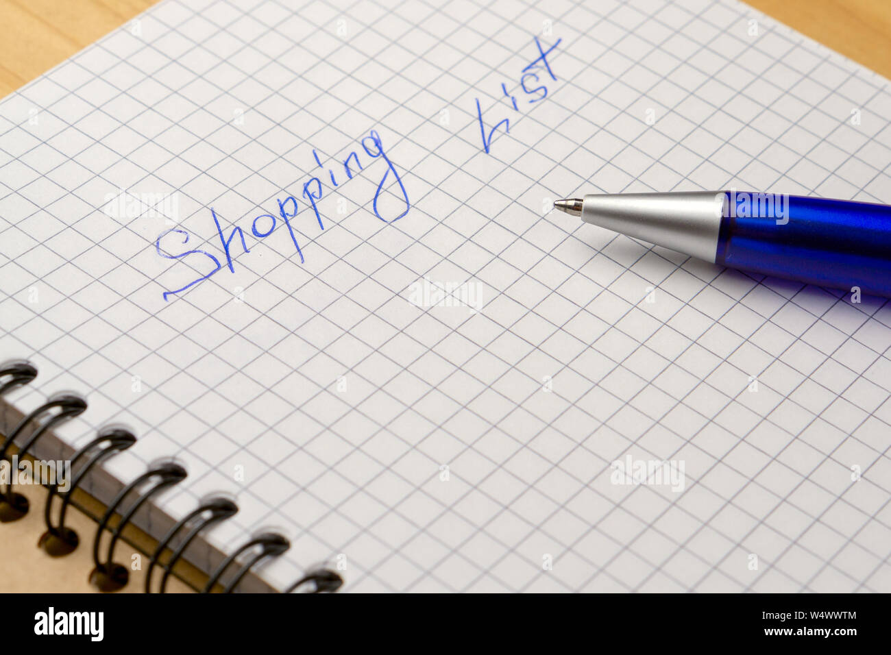 Blue pen on a notebook with sheets in a cage. Sign Shopping List. Side ...