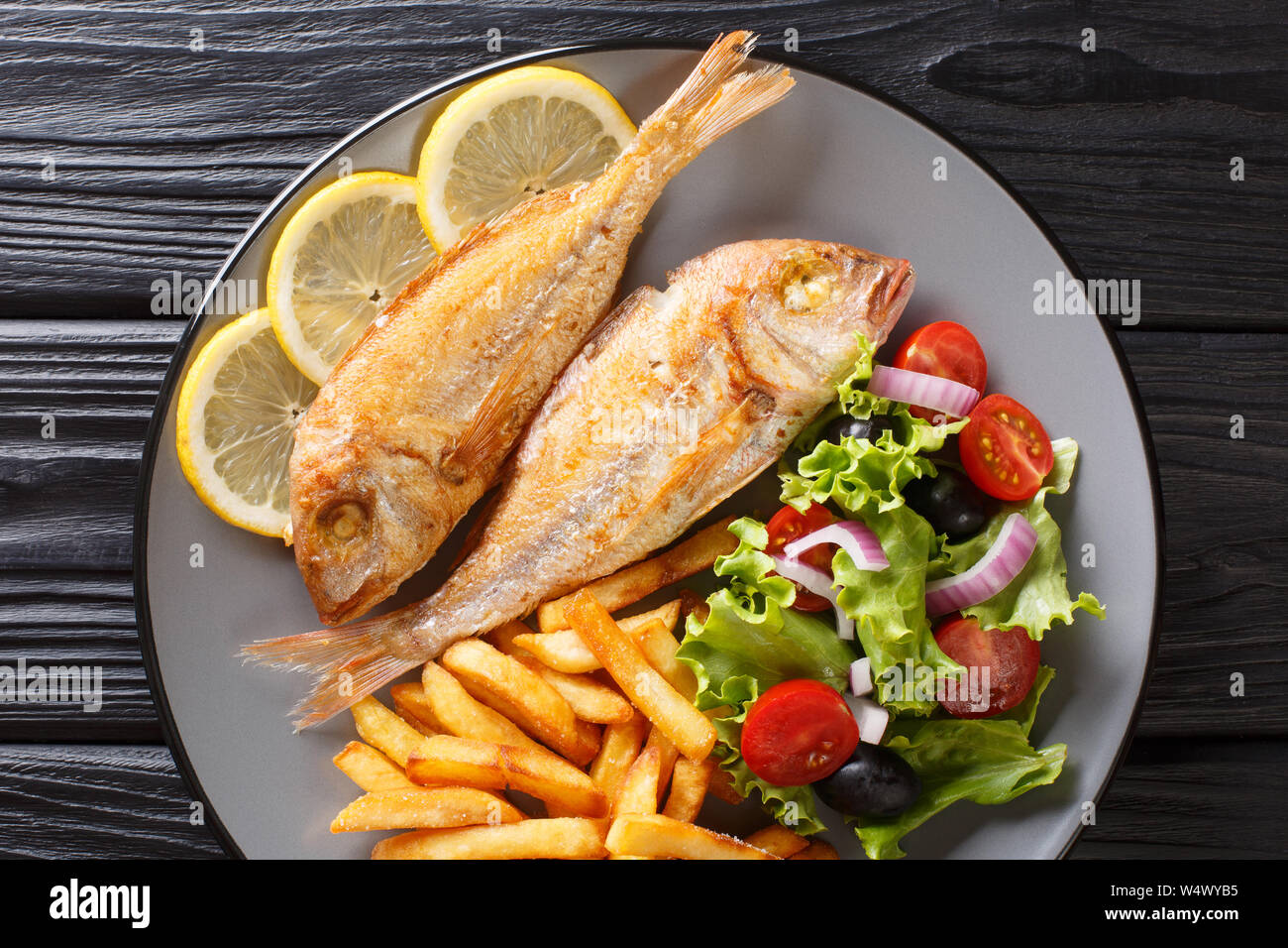 Fried pink dorado fish served with french fries and vegetable salad ...
