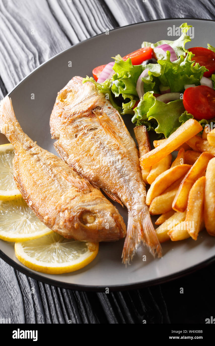 Fried pink dorado fish served with french fries and vegetable salad ...