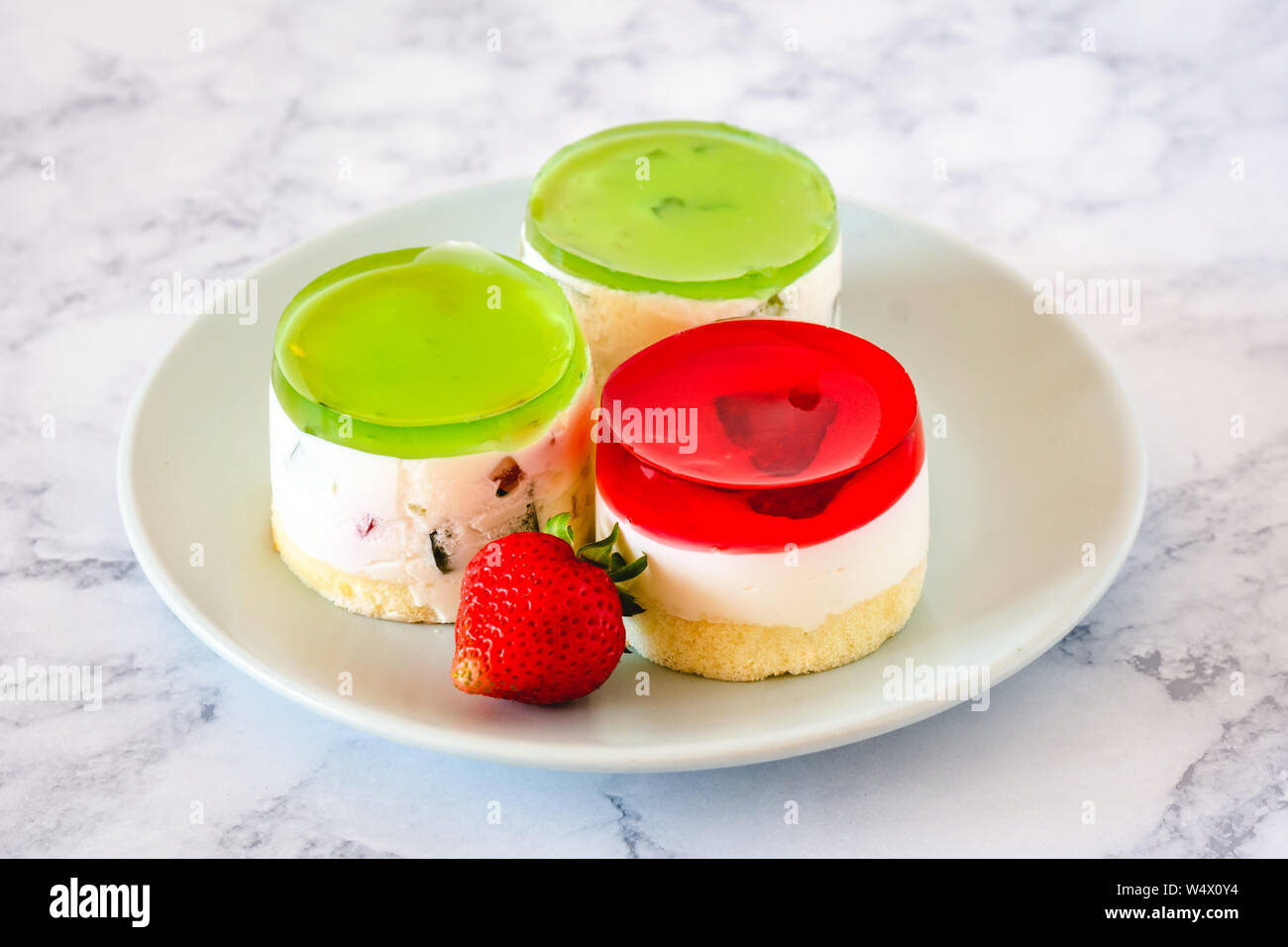 Mini round cold cheesecakes with fruit jelly and strawberries Stock ...