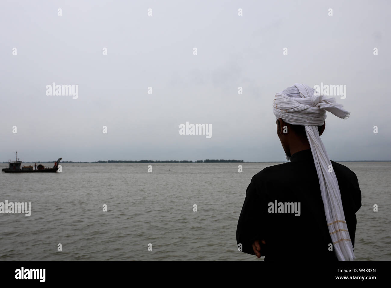 A flood victim looking at the char area on the other side of river ...