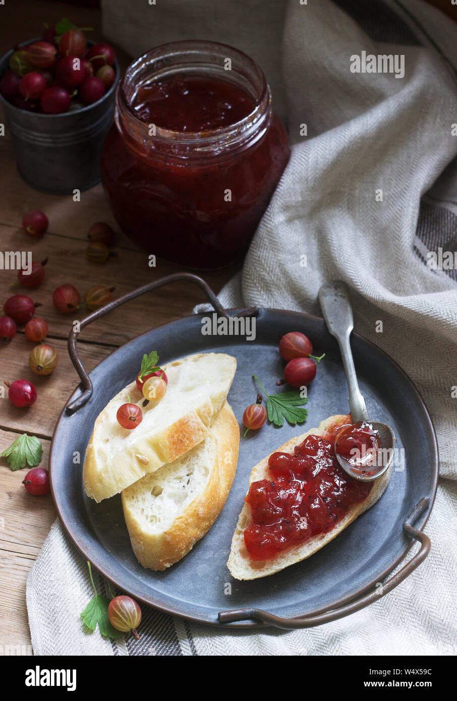 Toasts with gooseberry jam and gooseberries on a tin tray. Rustic style ...