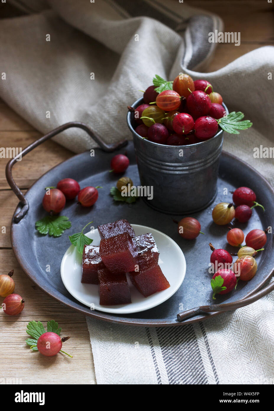 Gooseberry marmalade cubes and gooseberries on a tin tray. Rustic style ...