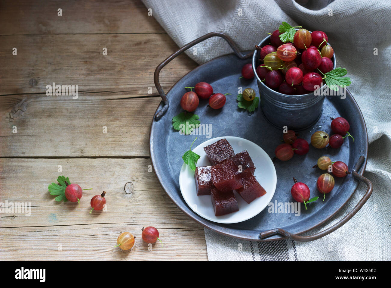 Gooseberry marmalade cubes and gooseberries on a tin tray. Rustic style ...