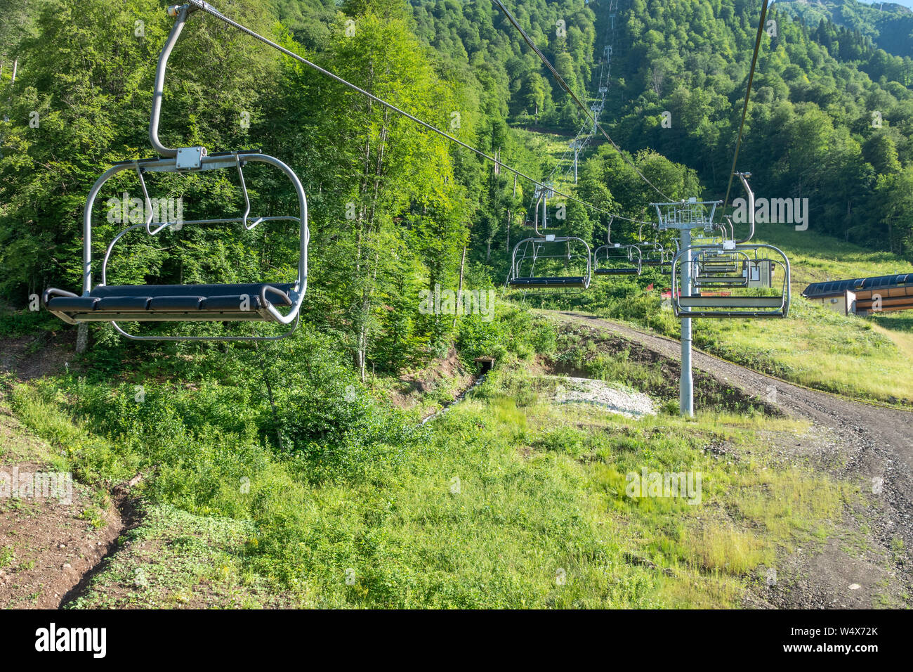 Cable car with open chair lifts in summer. Supports and cable car ...