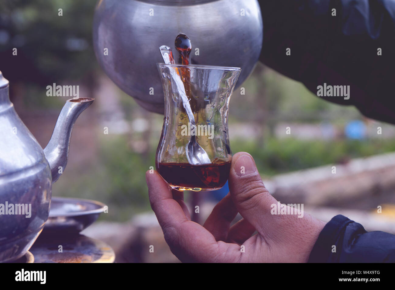 Man hand pouring Turkish tea into traditional glass on hand closeup ...