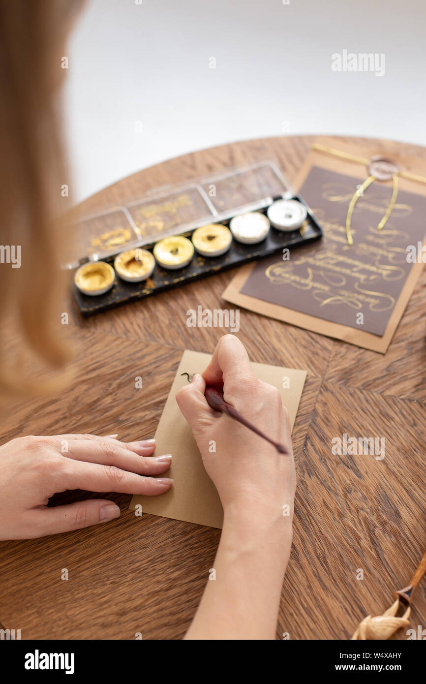 A calligrapher woman is holding a pen with ink in front of an empty ...