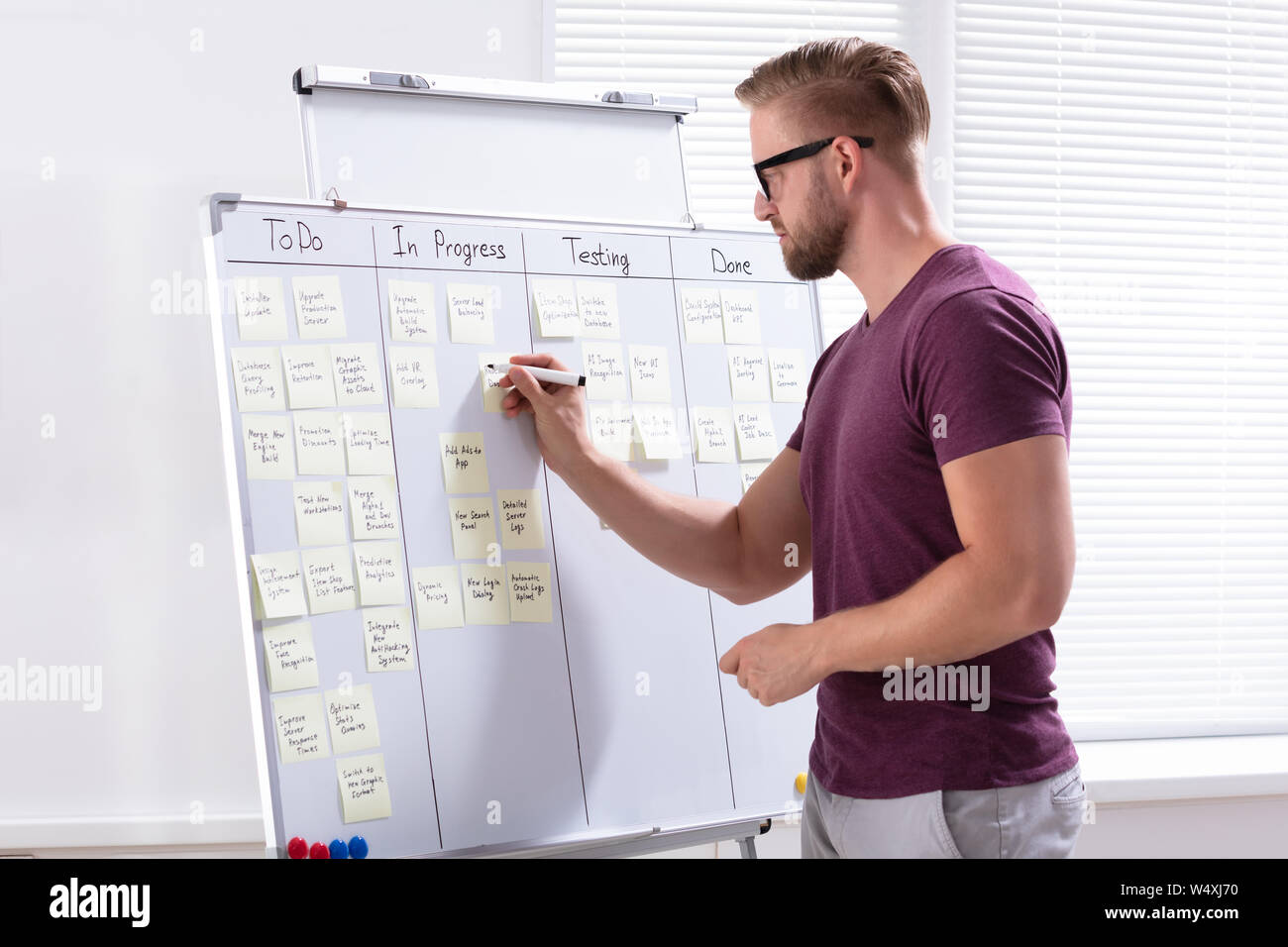 Side View Of Young Businessman Writing On Sticky Notes Attached To ...