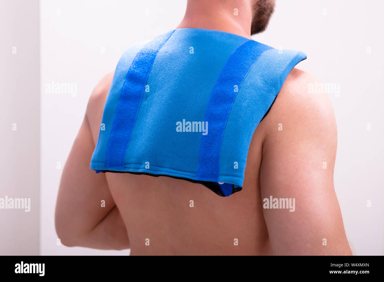 Rear View Of A Shirtless Man With Blue Ice Pack On His Shoulders And ...