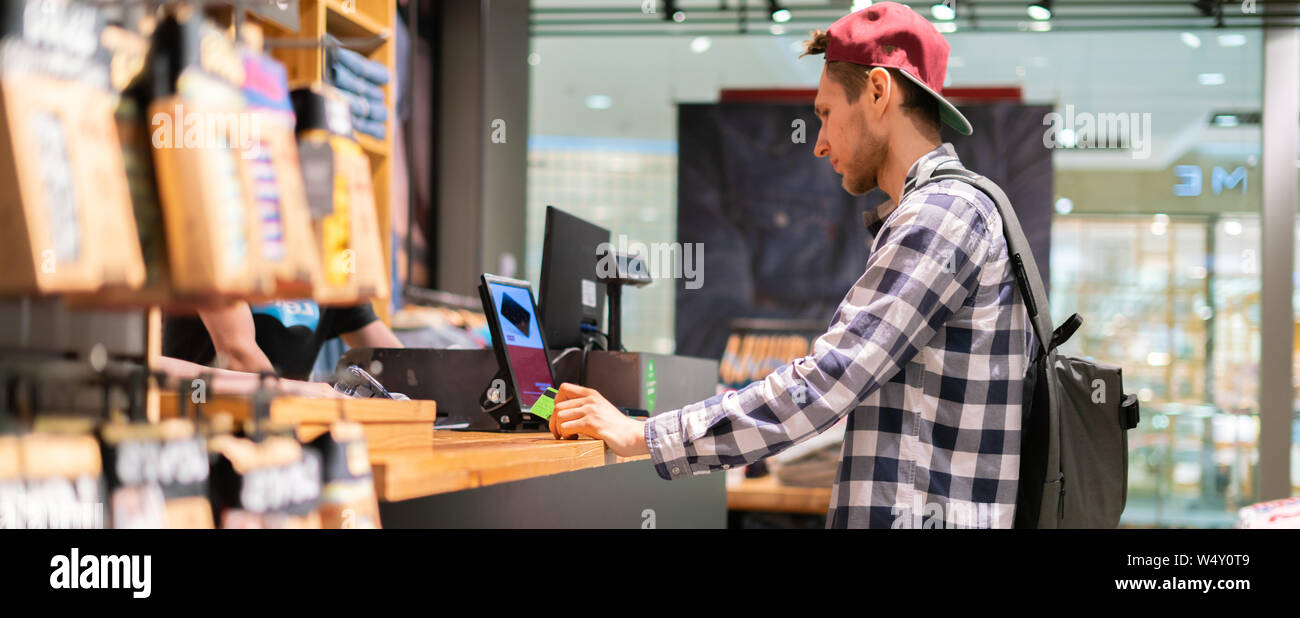 young man making a purchase and paying at the cash deck in the store ...