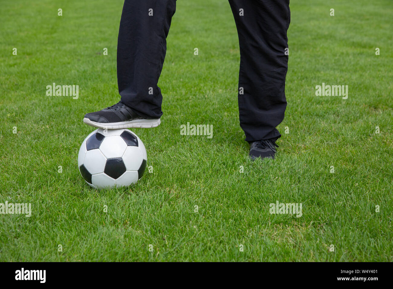 Legs with one foot standing on a soccer ball holding it in place Stock ...