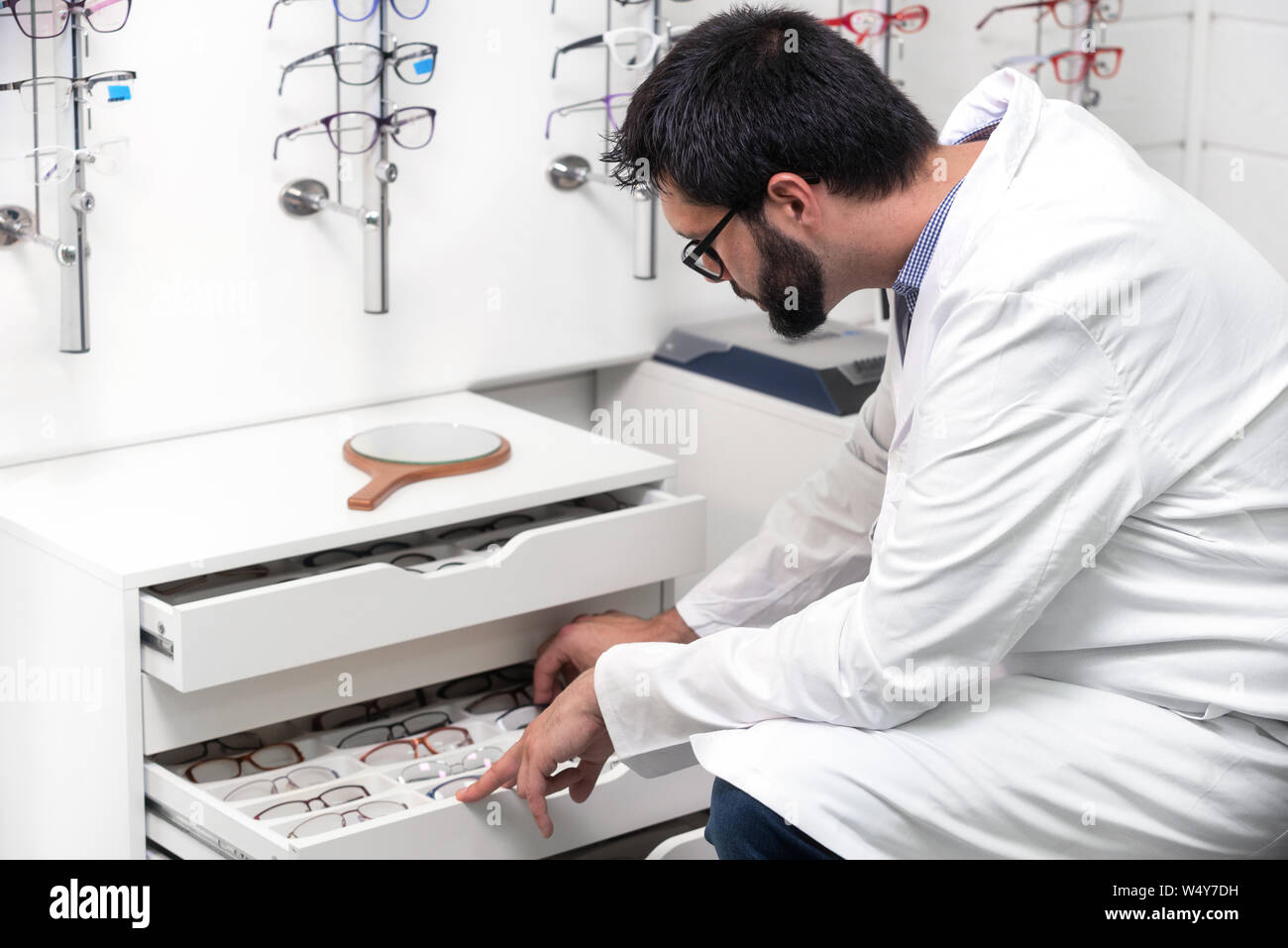 ophthalmologist choosing glasses from a drawer in the optical store ...