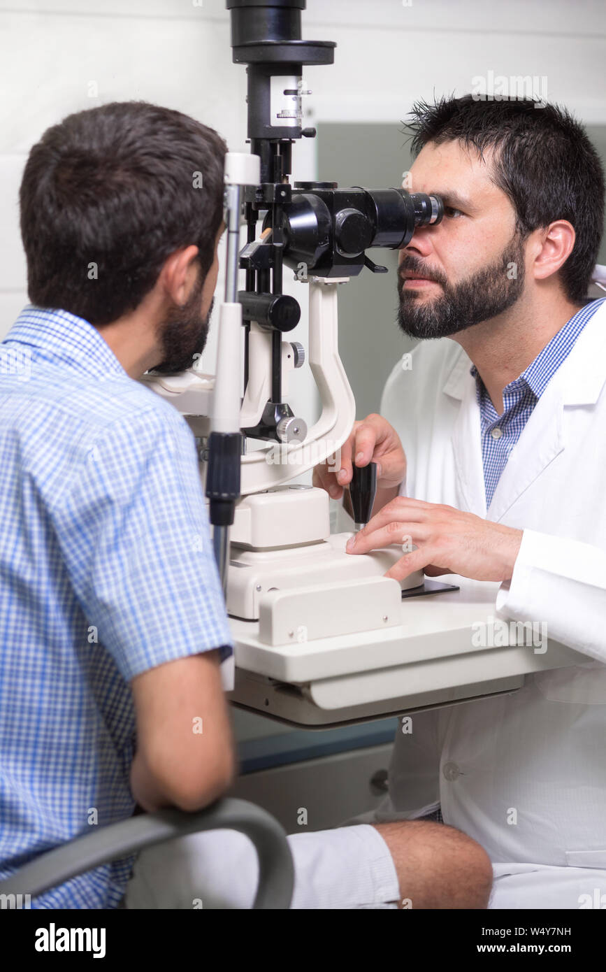 male doctor ophthalmologist is checking the eye vision of handsome ...