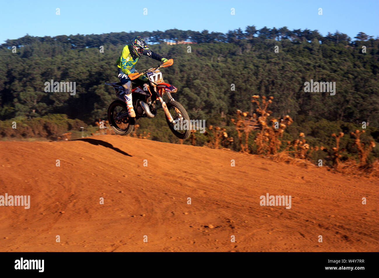 A motorcycle jumping forward on a slope of the dirt track on which it ...