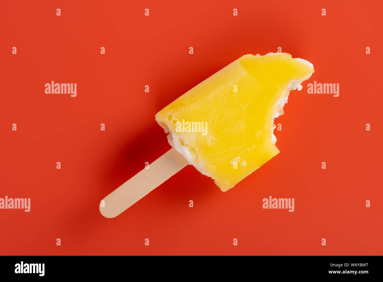 half eaten yellow popsicle with on an orange background Stock Photo - Alamy