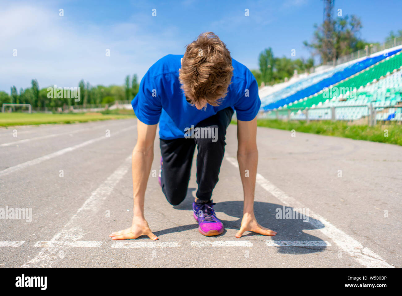 young runner athlete in the low start position on the sports track on ...