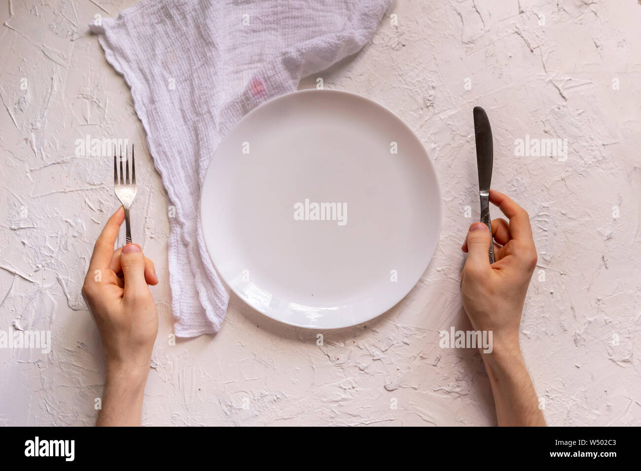 top view of person's hands on the table with empty plate design mock up ...